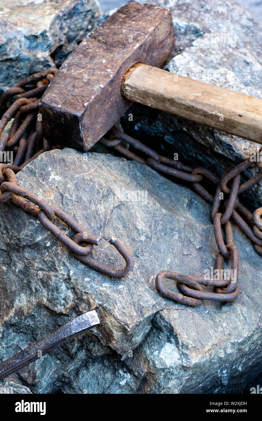 Rusty chain and old hammer on on gray stones. A torn chain is a symbol ...