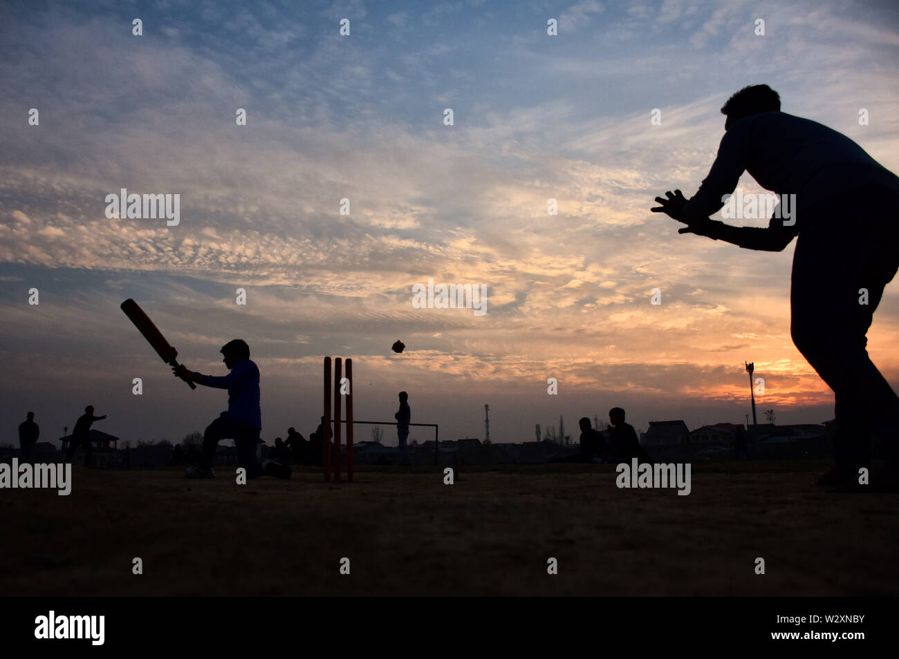 Youths play cricket during sunset in a field in Srinagar, in Indian ...
