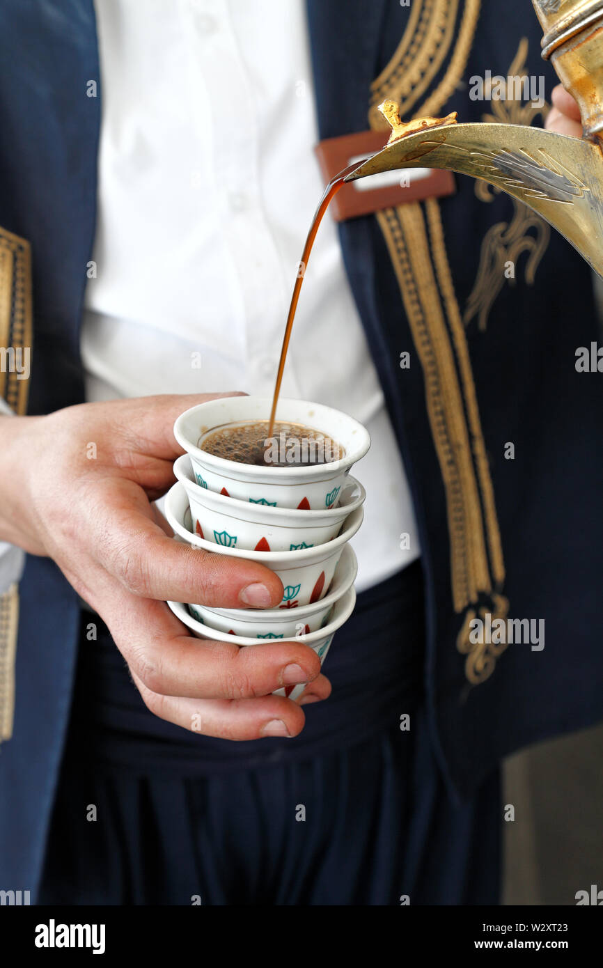 Man in traditonal clothes pouring coffee into arabic cups Stock Photo ...