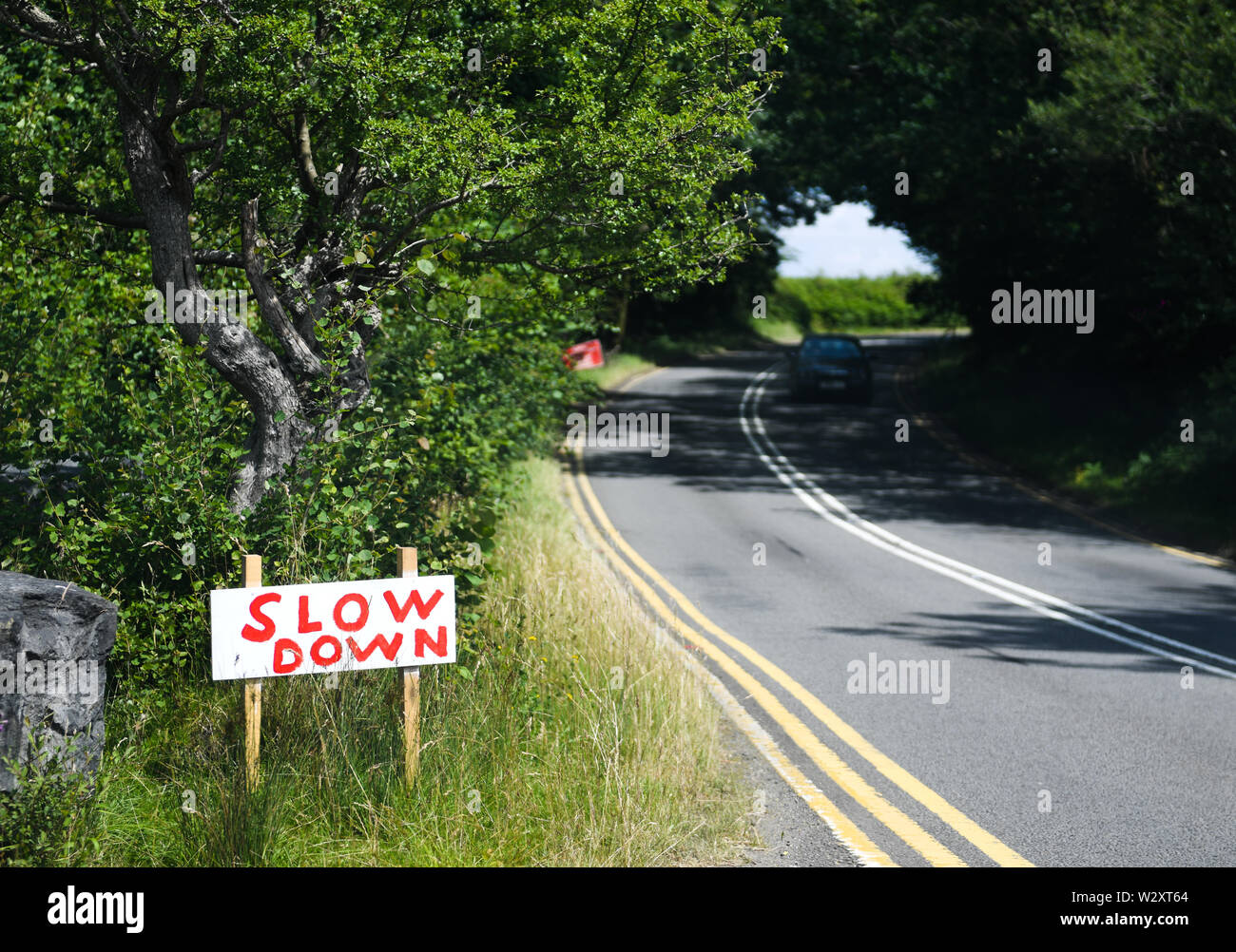 Handmade slow down road sign on the side of a road telling drivers to ...