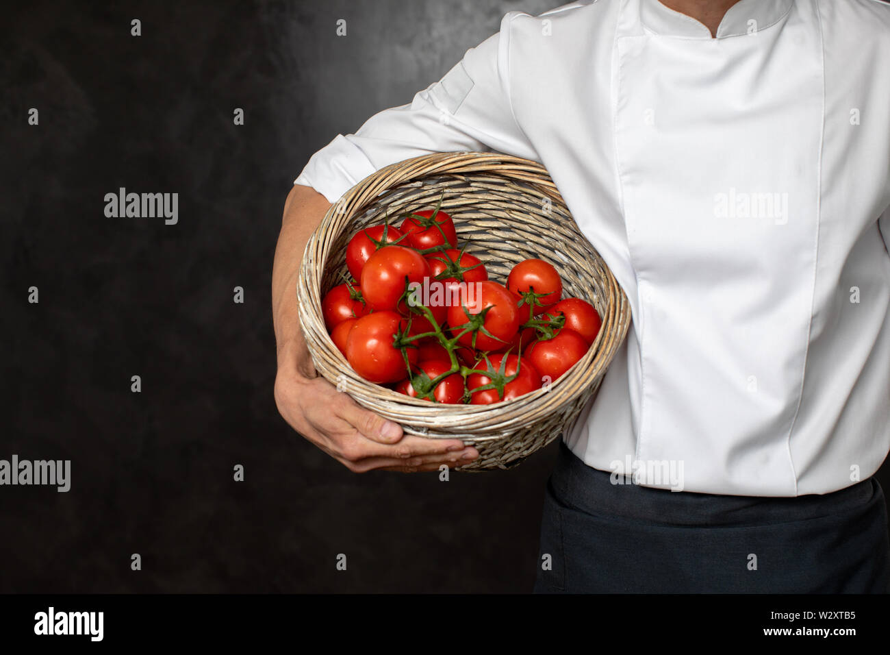 Faceless chef holding basket with ripe tomatoes Stock Photo - Alamy