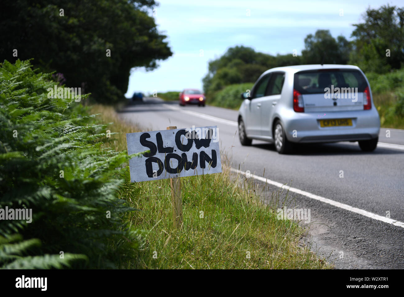 Handmade slow down road sign on the side of a road telling drivers to ...