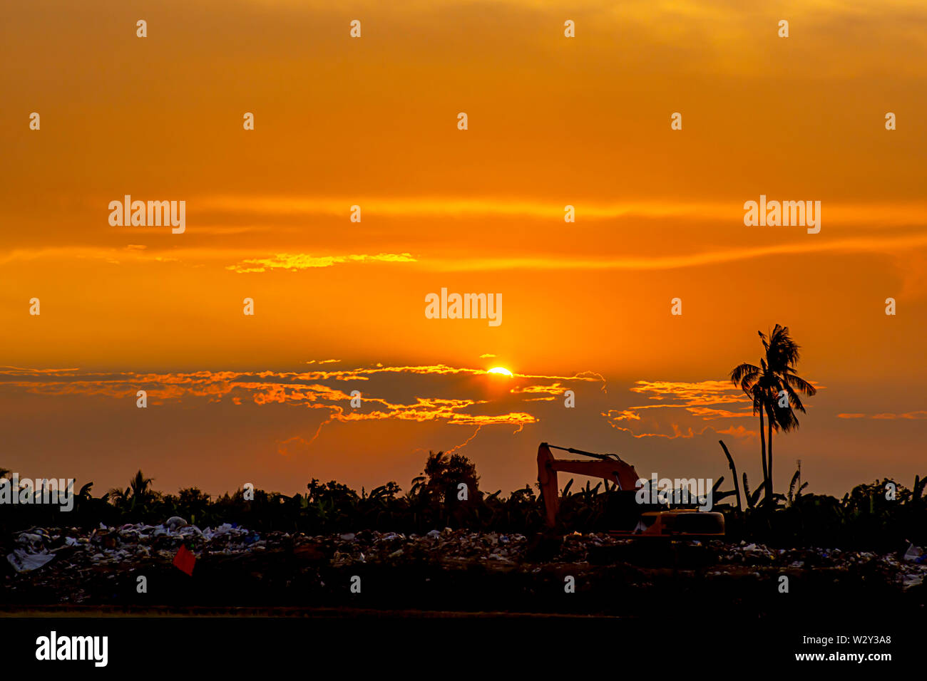 Sunset the evening light through the clouds and the shadow of Backhoe ...
