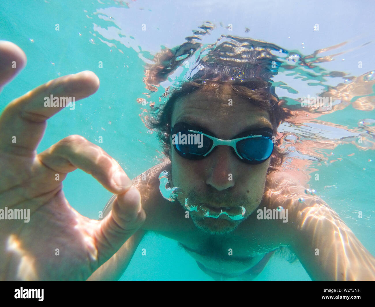 Underwater view of swimmer doing the ok sign in the sea Stock Photo - Alamy