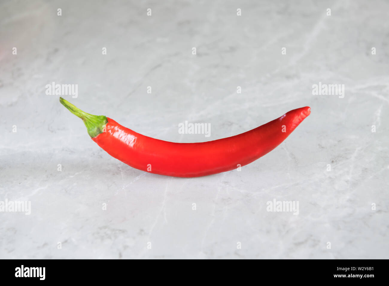 One hot chili pepper on grey marble background, crescent shaped. use ...