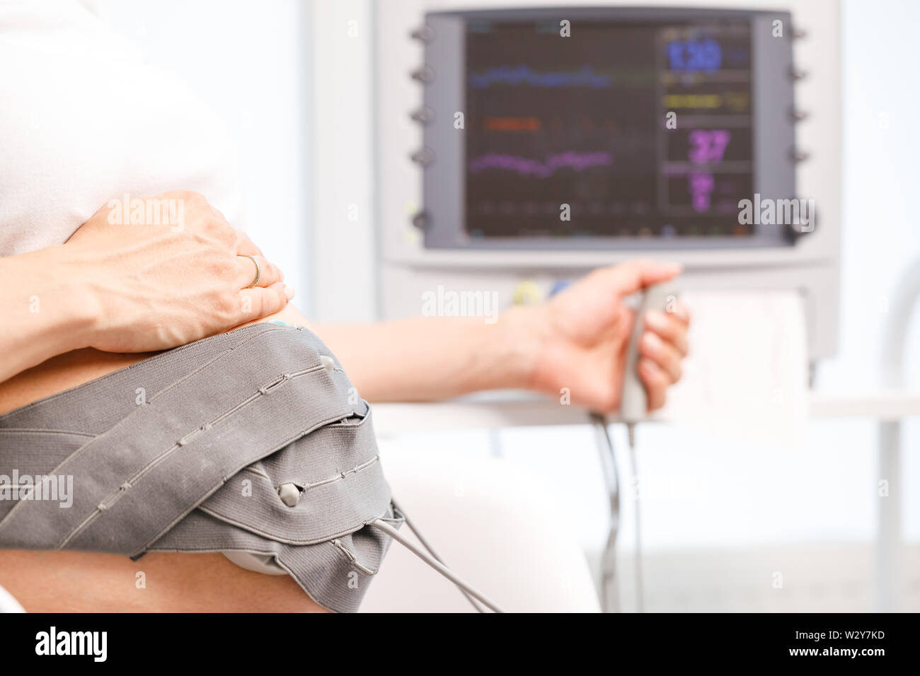 Pregnant woman sitting in clinic performing cardiotocography (CTG). The ...