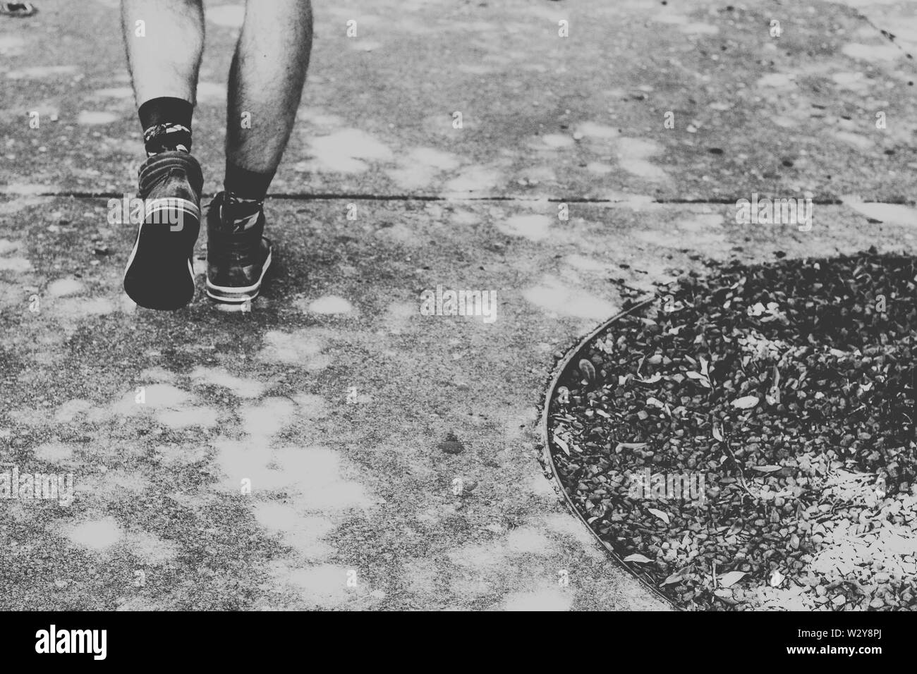 Closeup to male's feet walking on cement with dirt on the side shot in ...