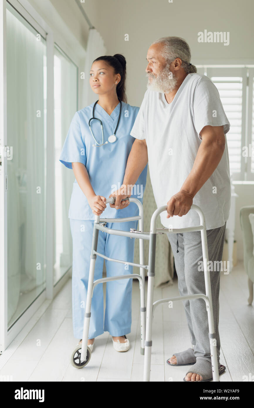 Healthcare worker with man using walking support Stock Photo - Alamy