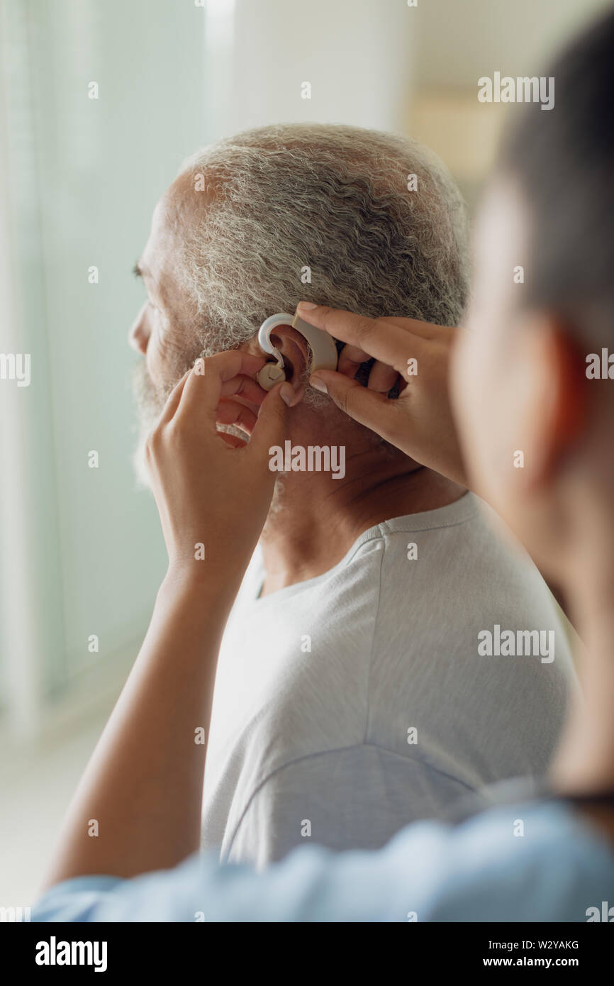 Healthcare worker putting hearing aid Stock Photo - Alamy
