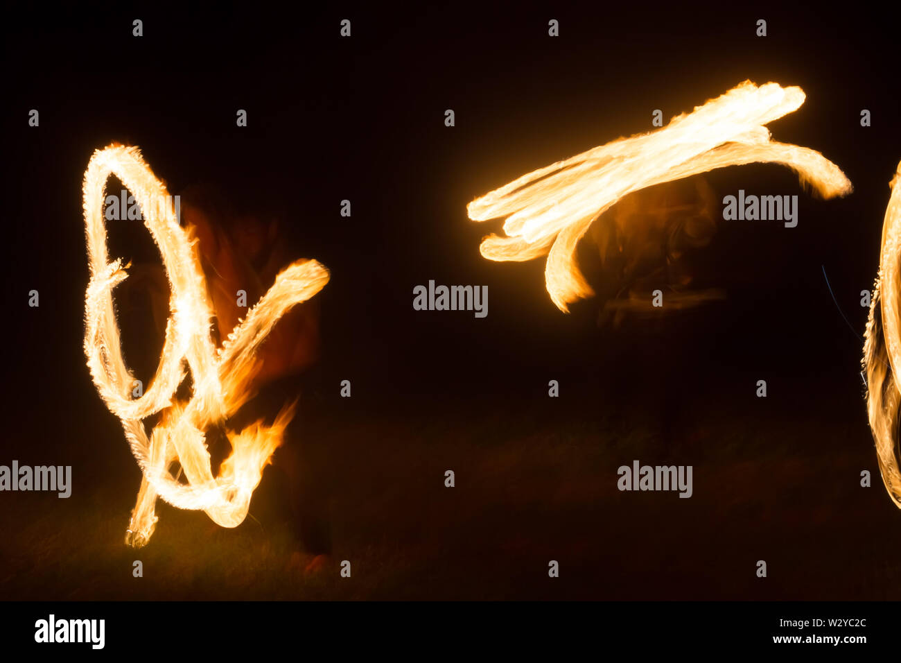 An artist shows a fire show at night spinning torches, circles of fire ...