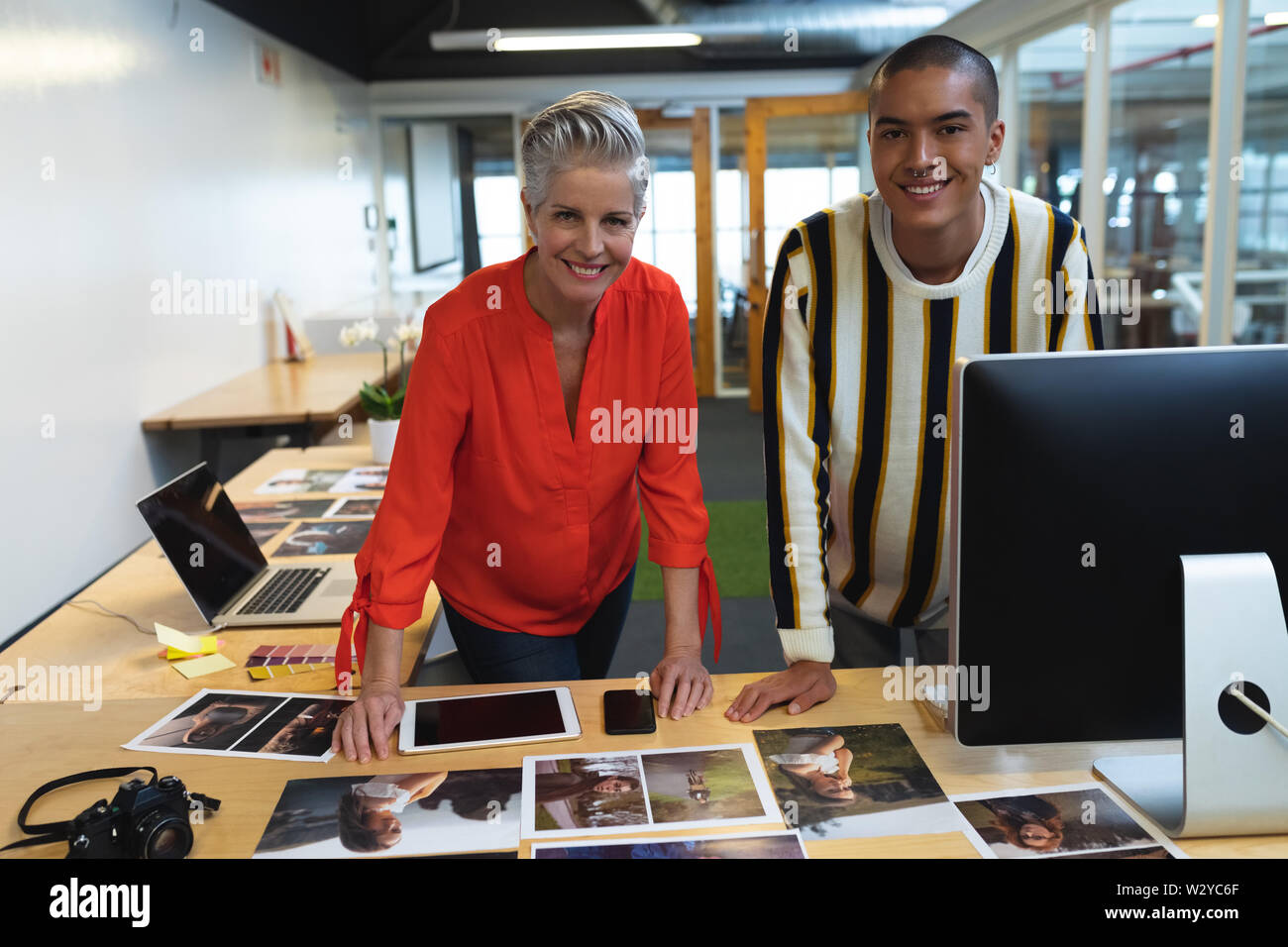 Male and female graphic designers standing together at desk in office ...