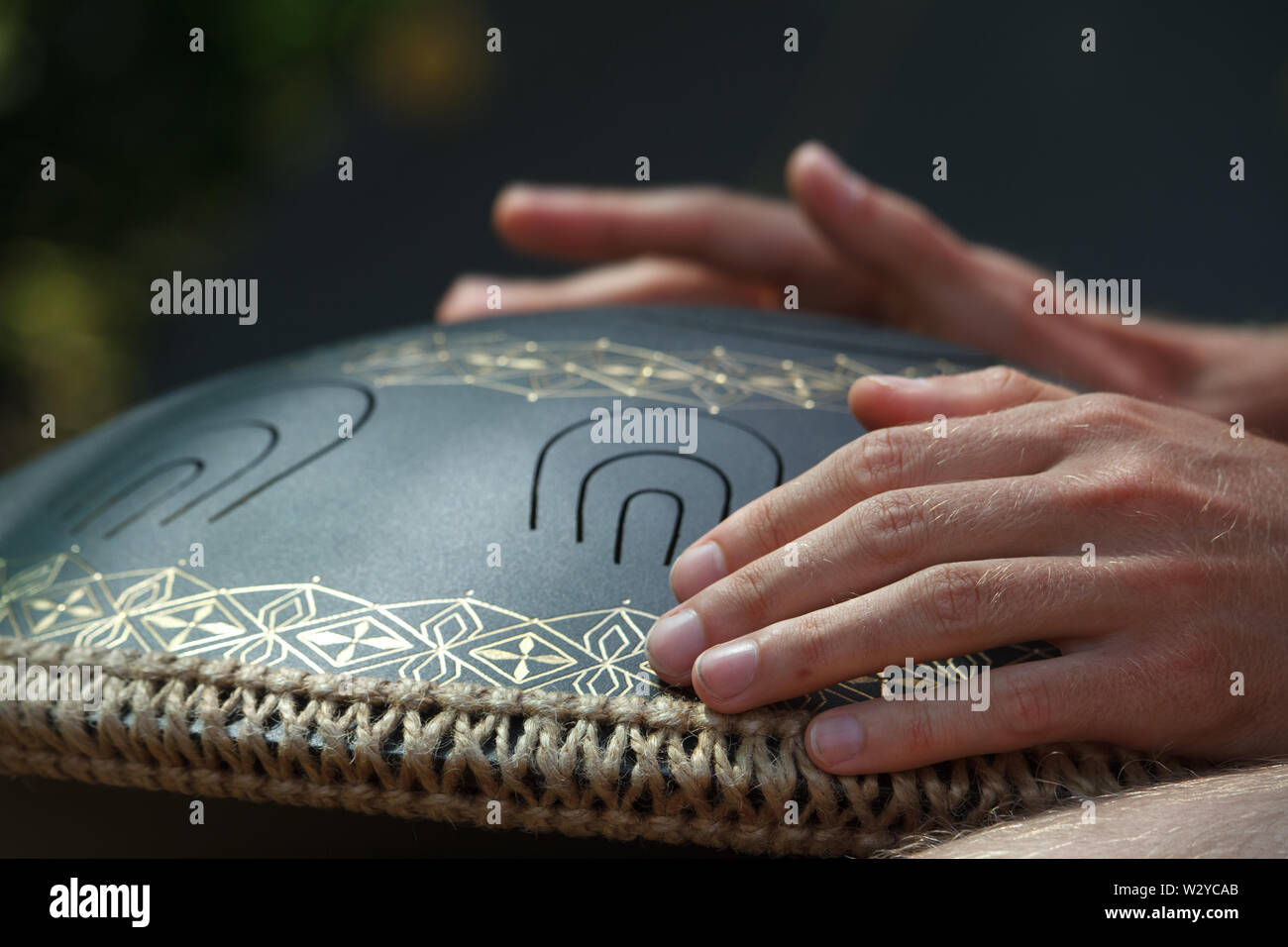 Closeup of a mans hand playing on modern musical instrument Hand pan or ...