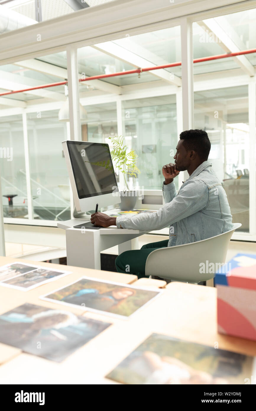 Male graphic designer using graphic tablet at desk Stock Photo - Alamy