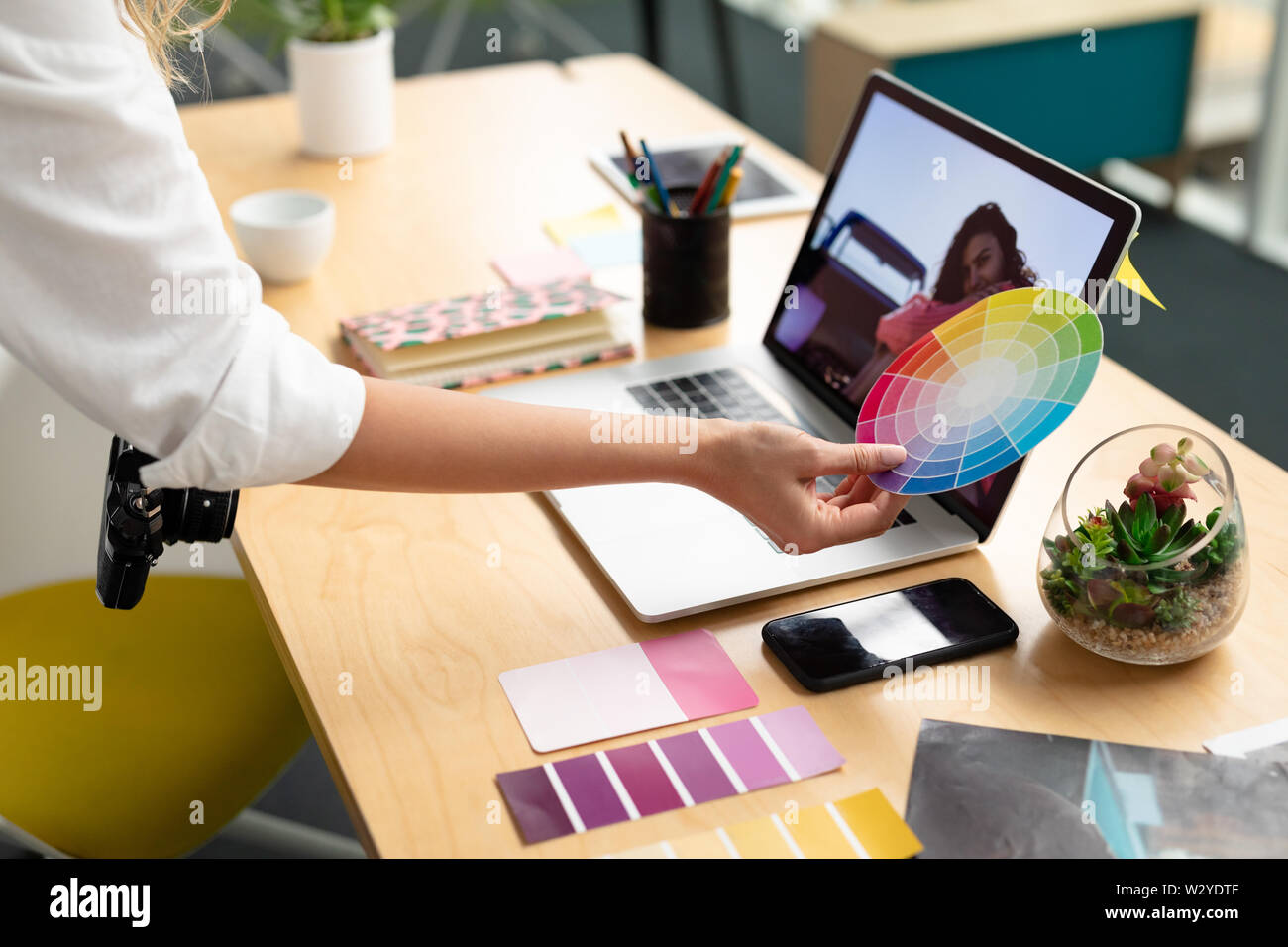 Female graphic designer holding a color swatch at desk Stock Photo - Alamy