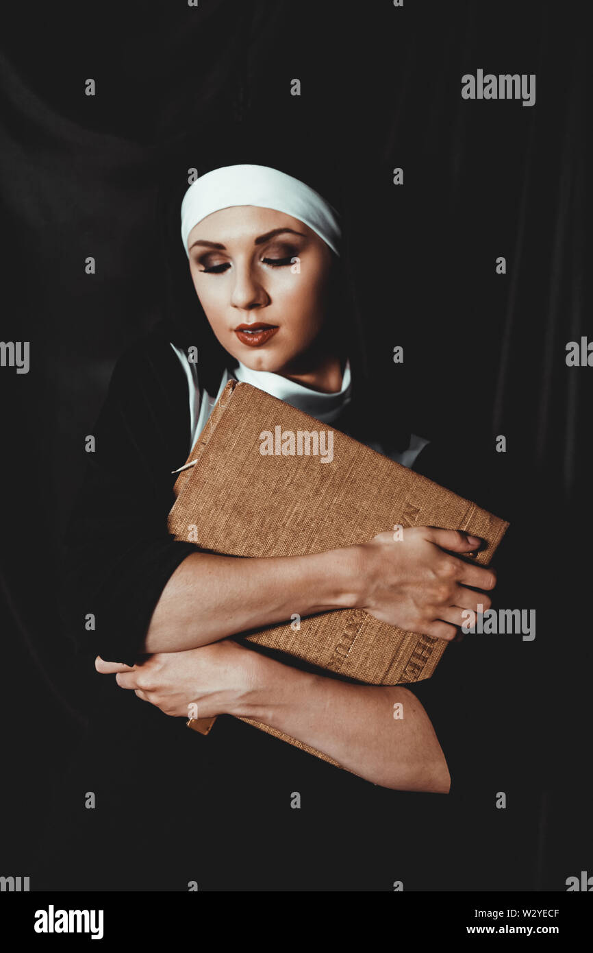 Beautiful young nun in religion black suit holds Bible and posing on ...