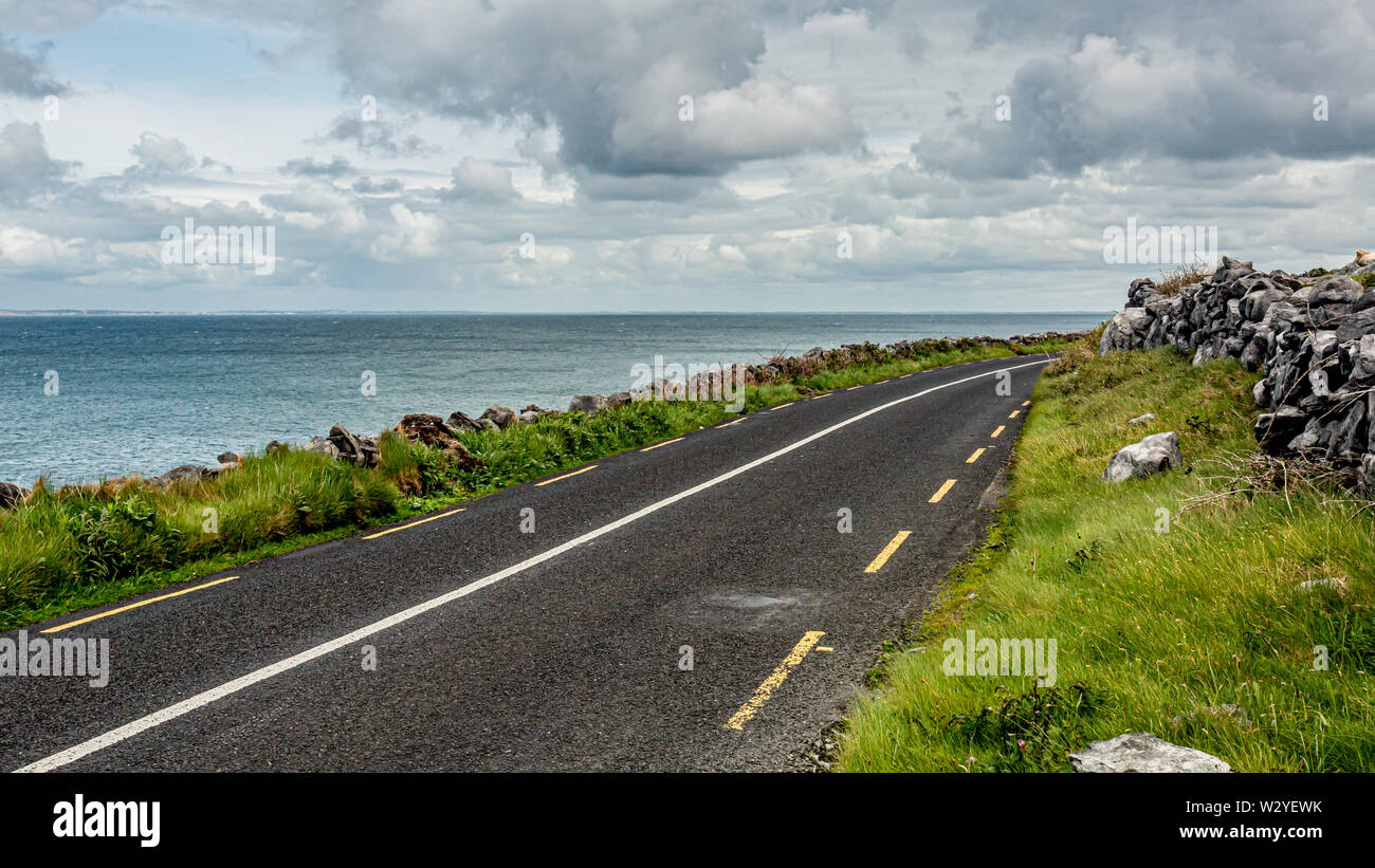 Irish landscape with the sea and the rural coastal R477 road along the ...