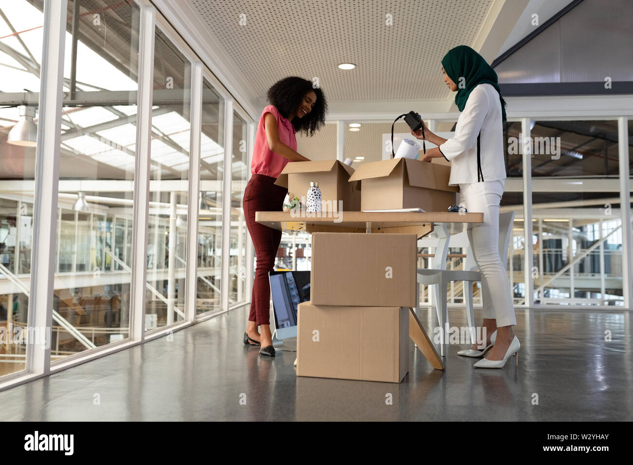 Female executives unpacking cardboard boxes in office Stock Photo - Alamy