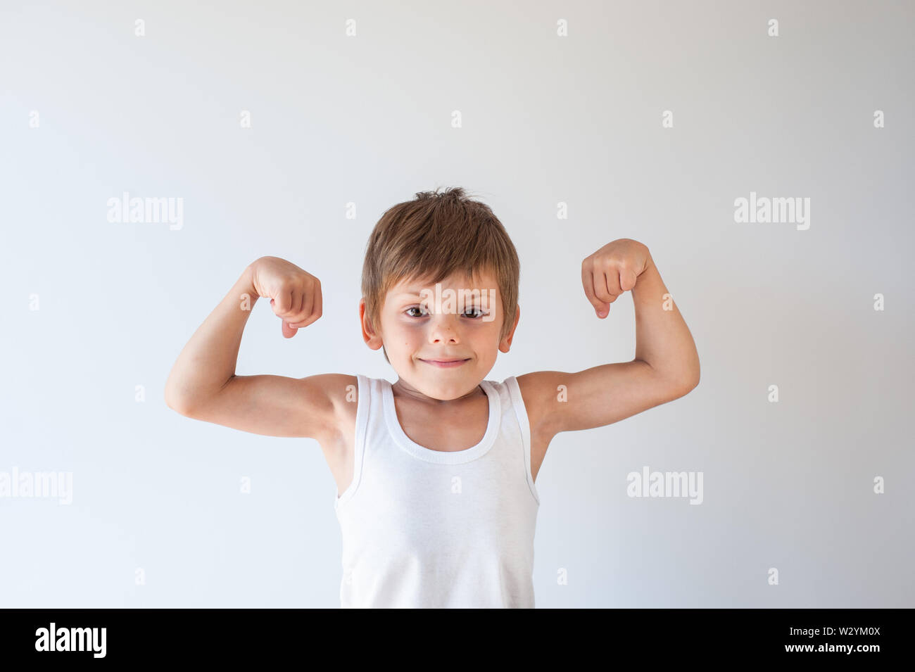 strong little boy in white tank top showing hid muscle smiling on ...