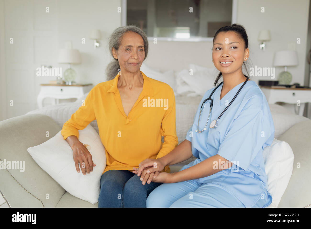 Healthcare worker and woman sitting on couch Stock Photo - Alamy