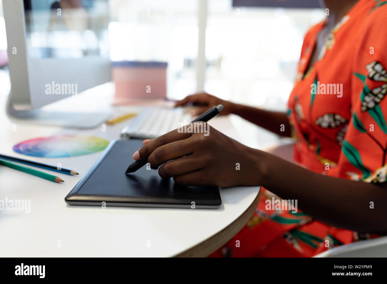 Female Graphic designer using graphic tablet at desk in office Stock ...