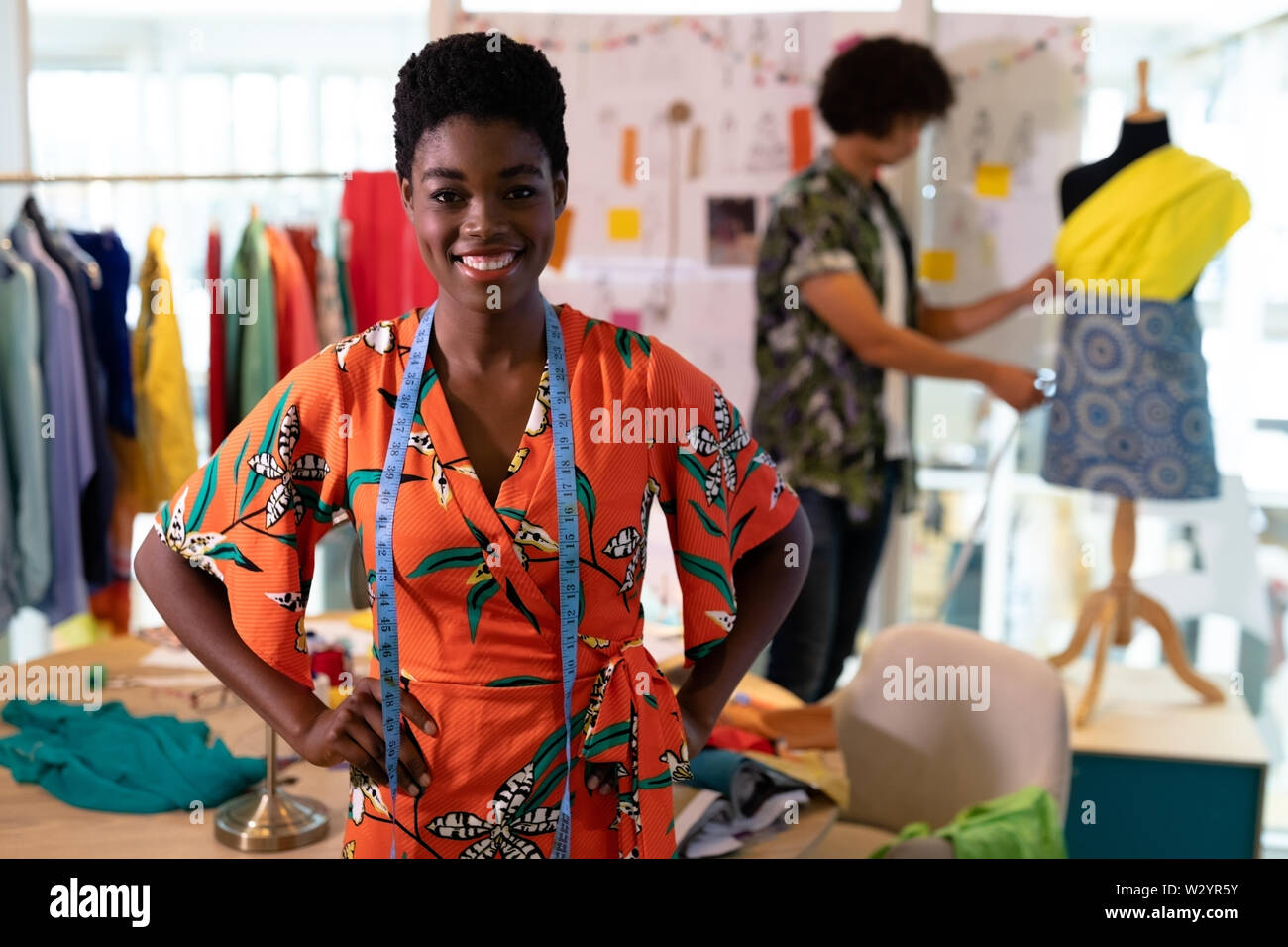 Female fashion designer standing with hands on hip in design studio ...