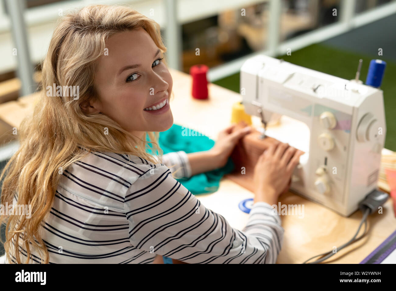 Female fashion designer using sewing machine on a table in design ...