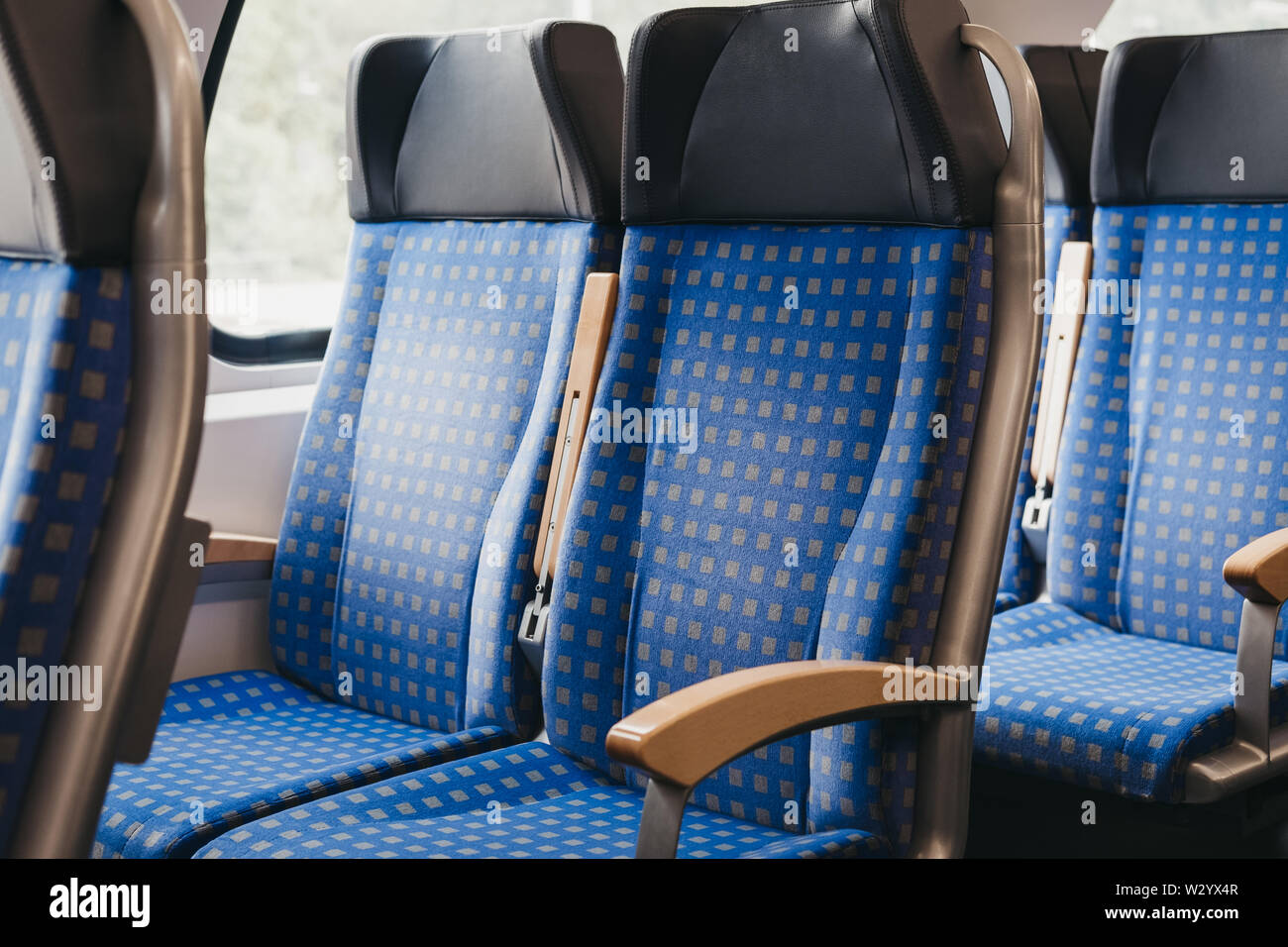 Rows of blue fabric seats with leather headrests inside empty modern ...