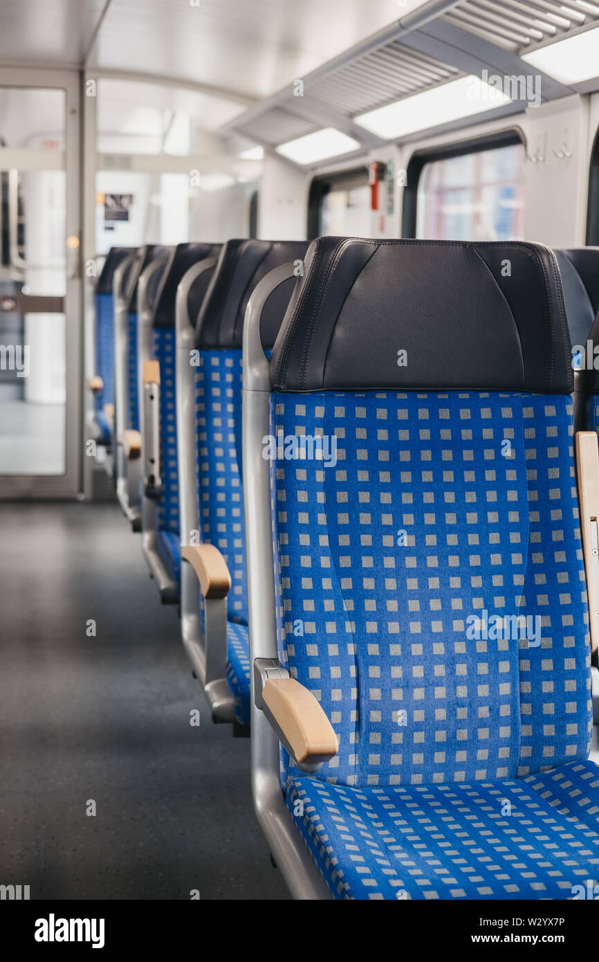 Rows of blue fabric seats with leather headrests on one side of an ...