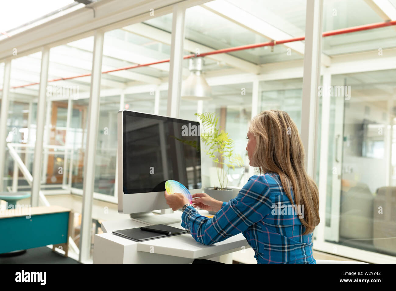 Female graphic designer looking at color swatch at desk Stock Photo - Alamy