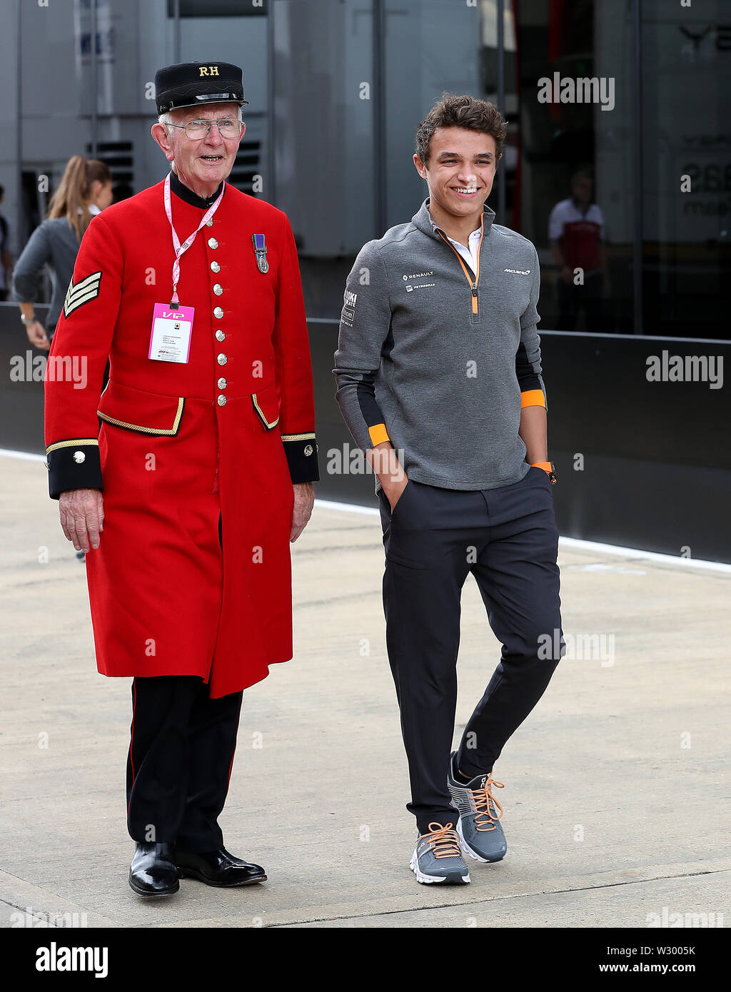 McLaren driver Lando Norris (right) walks through the paddock with a ...