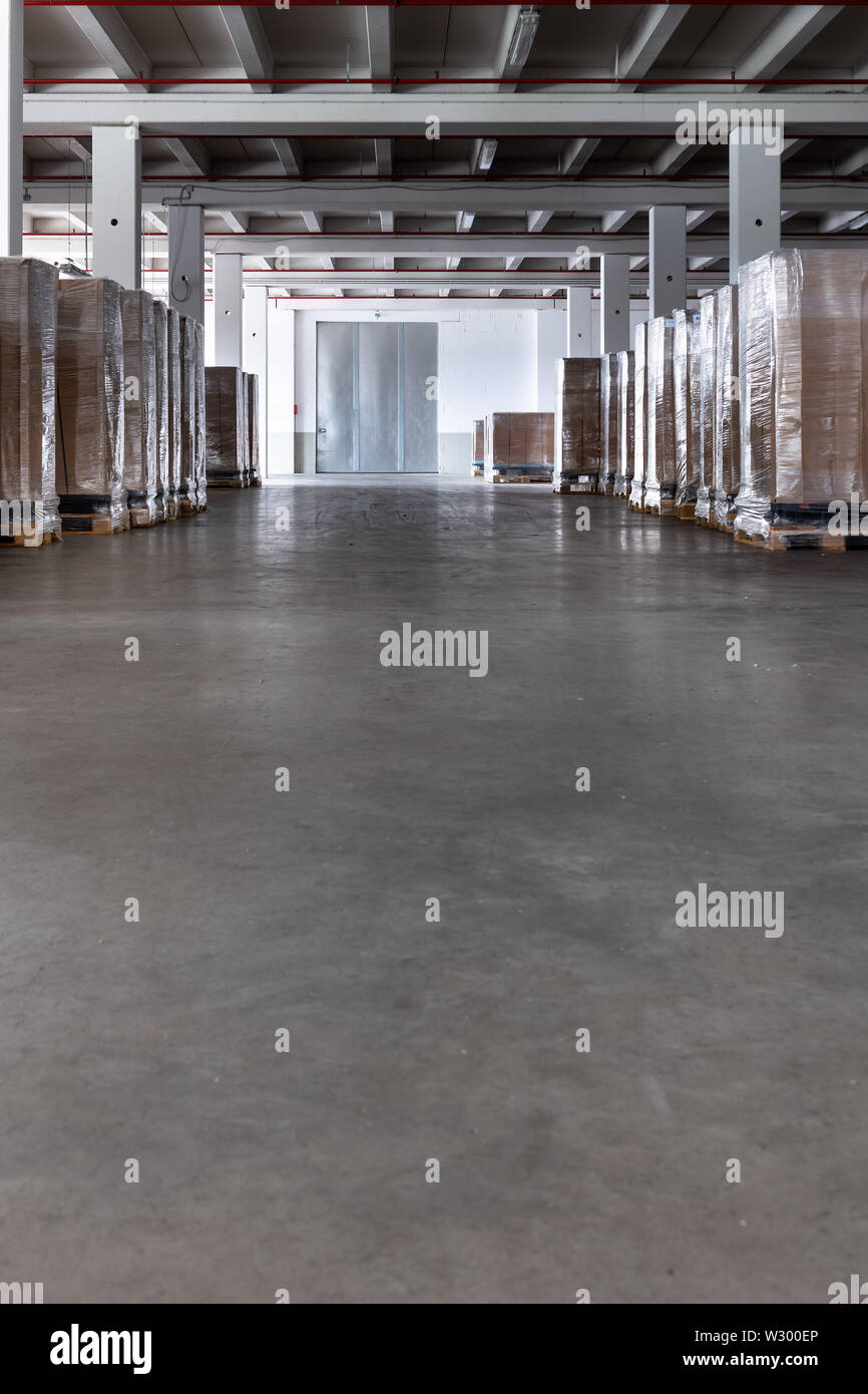 Warehouse with concrete floor and packed cartons neatly stacked on ...