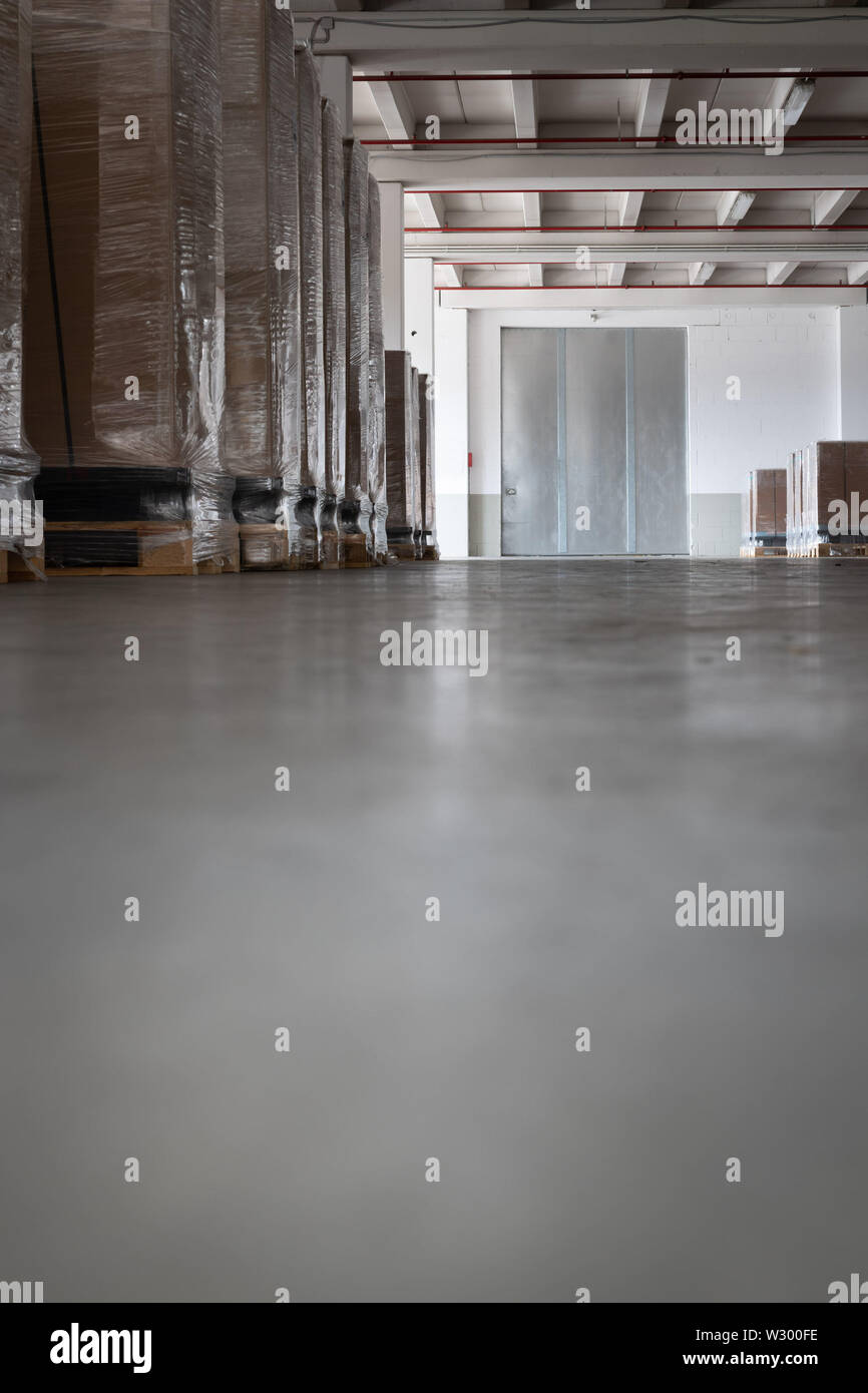 Warehouse with concrete floor and packed cartons neatly stacked on ...