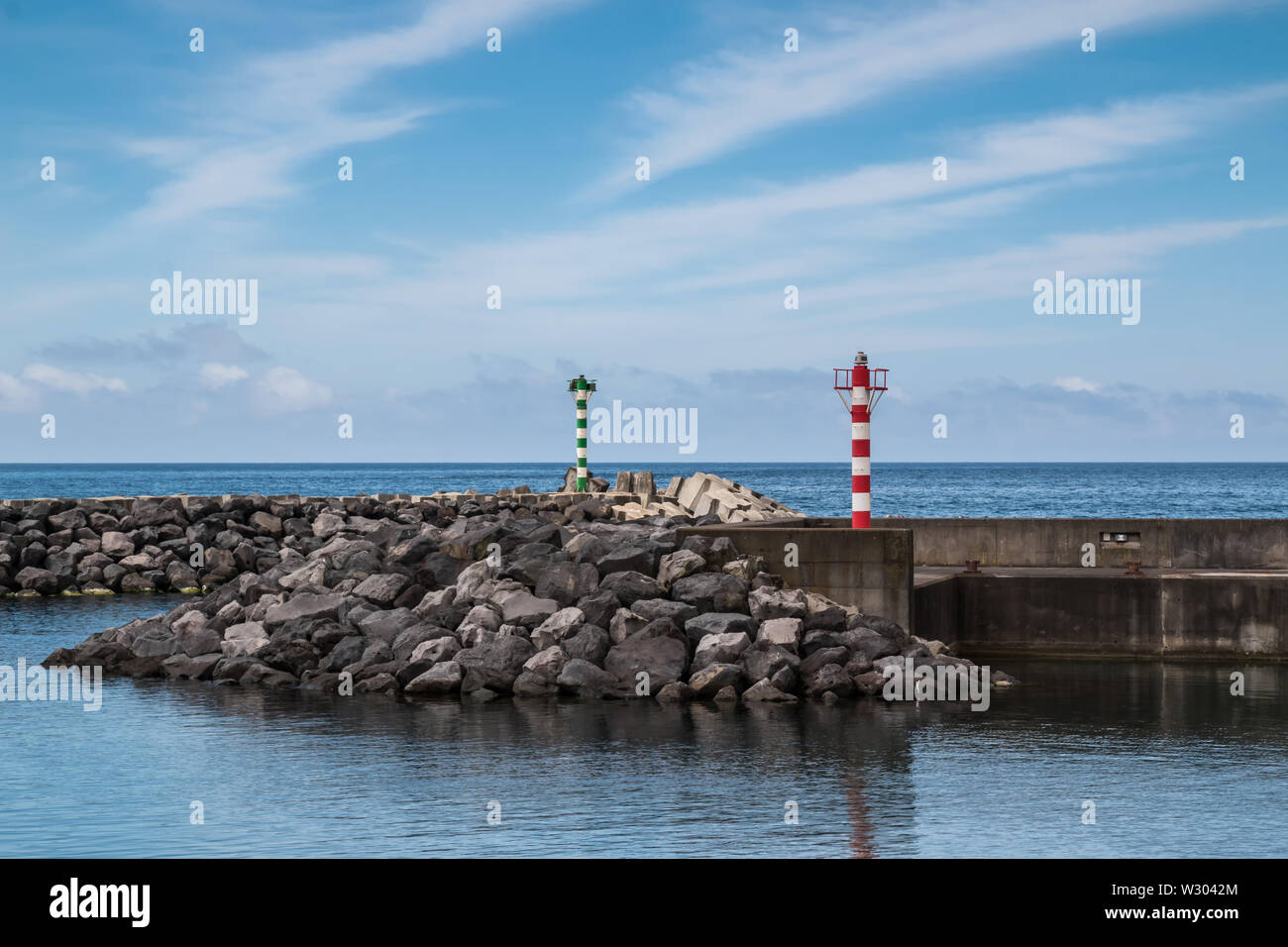 Entrance to the port separated by a stone wall with two columns, green ...