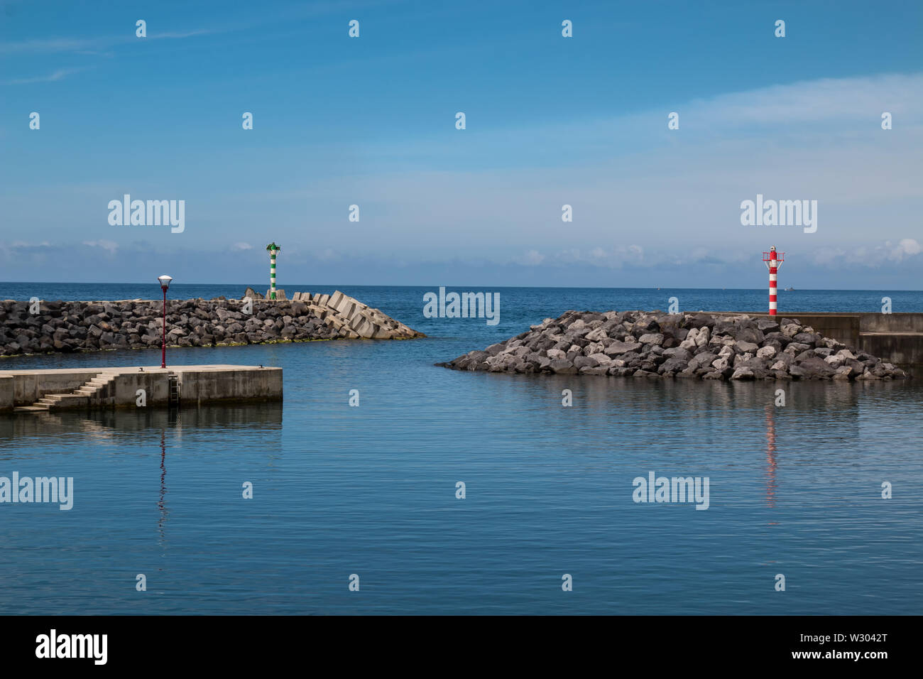 Entrance to the port separated by a stone wall with two columns, green ...