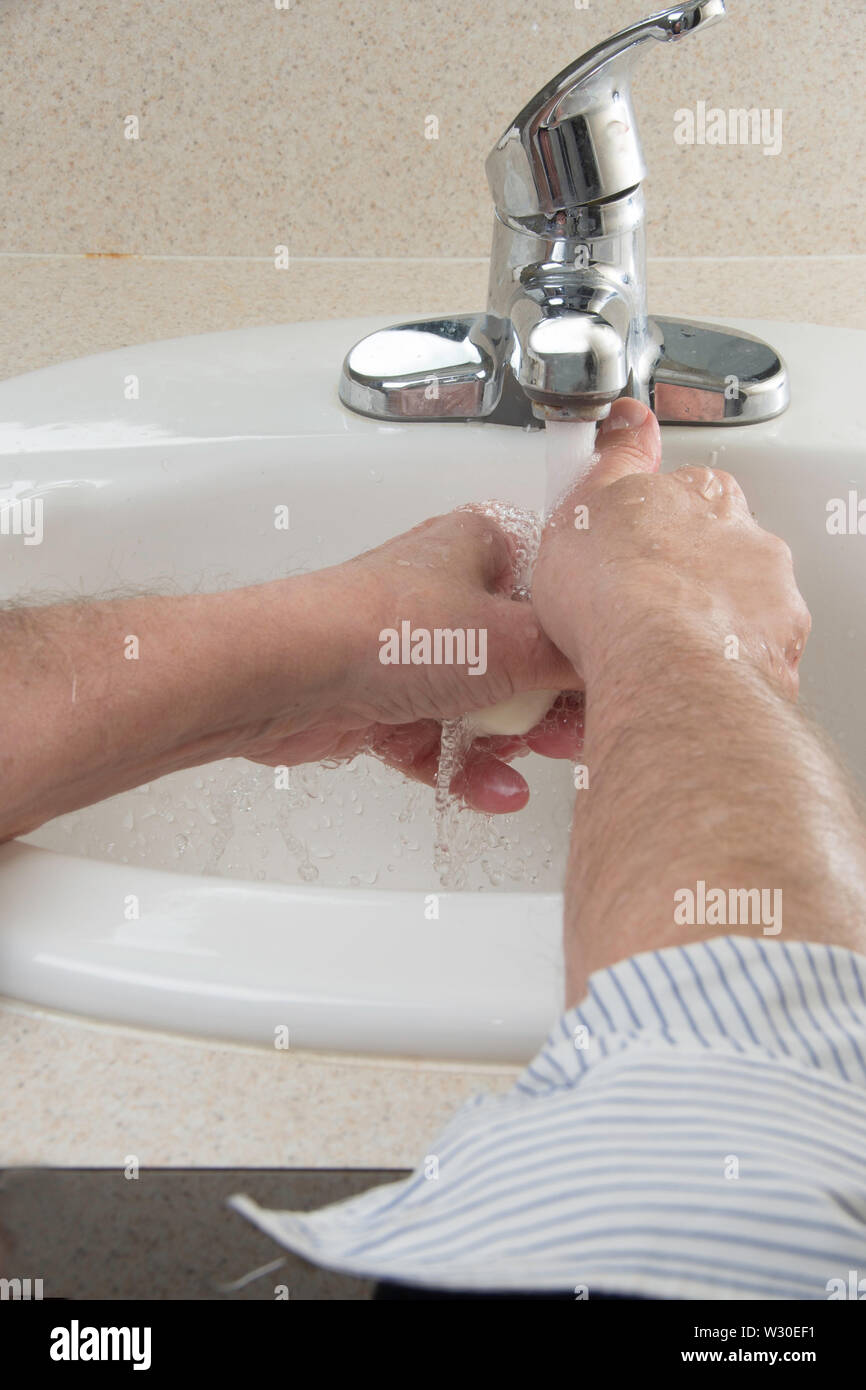 Person lathering hands for hygiene in a bathroom sink Stock Photo - Alamy