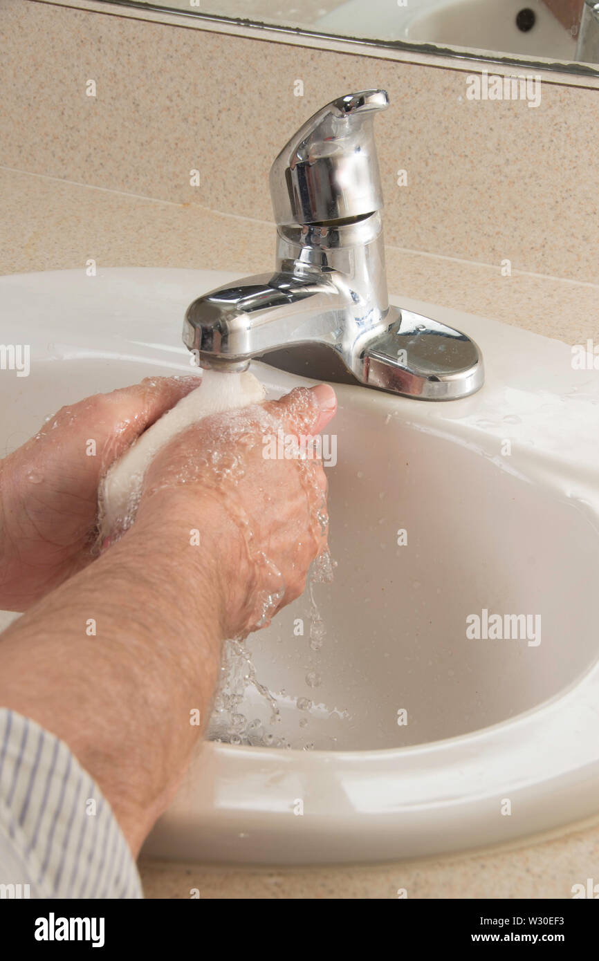 Person lathering hands for hygiene in a bathroom sink Stock Photo - Alamy