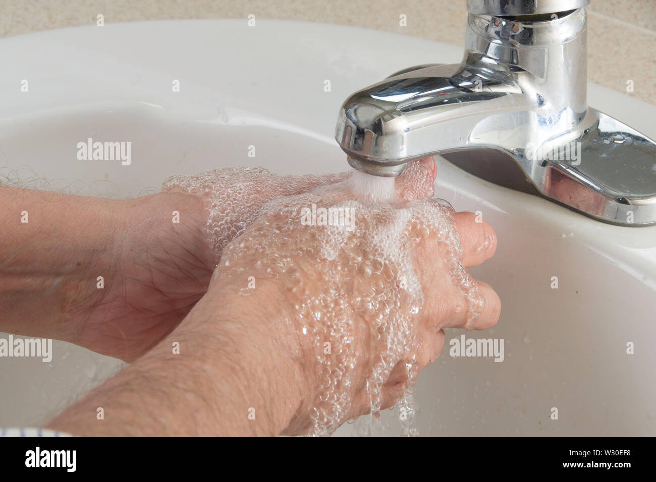 Person lathering hands for hygiene in a bathroom sink Stock Photo - Alamy