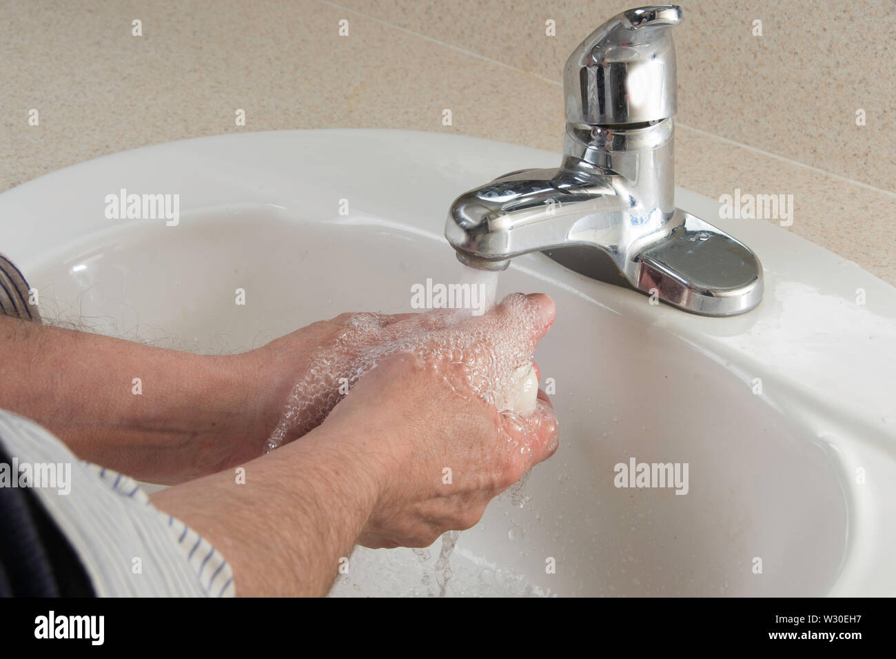 Person lathering hands for hygiene in a bathroom sink Stock Photo - Alamy