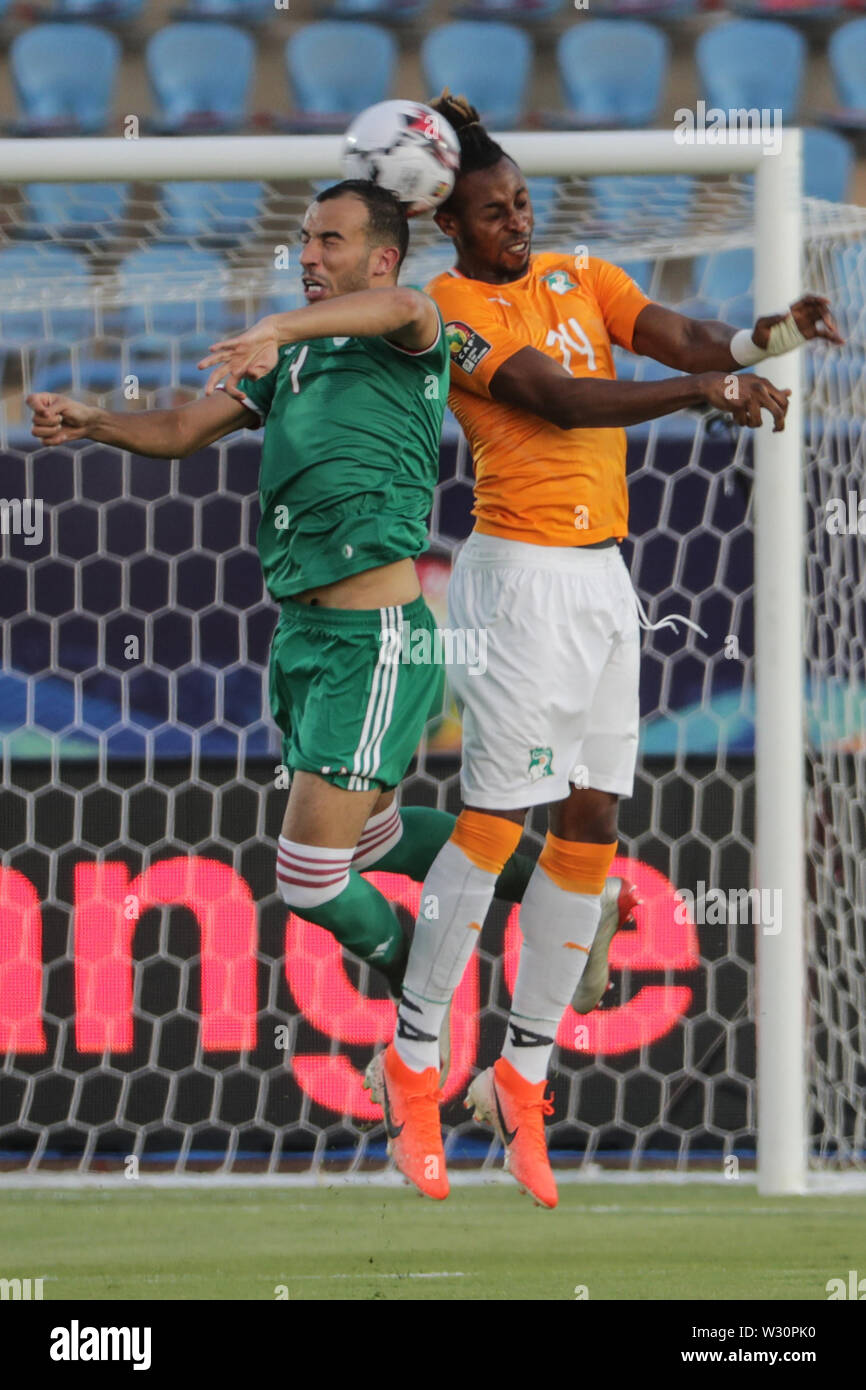 Suez, Egypt. 11th July, 2019. Cote d'Ivoire's Jonathan Kodja (R) and Algeria's Djamel Benlamri ...