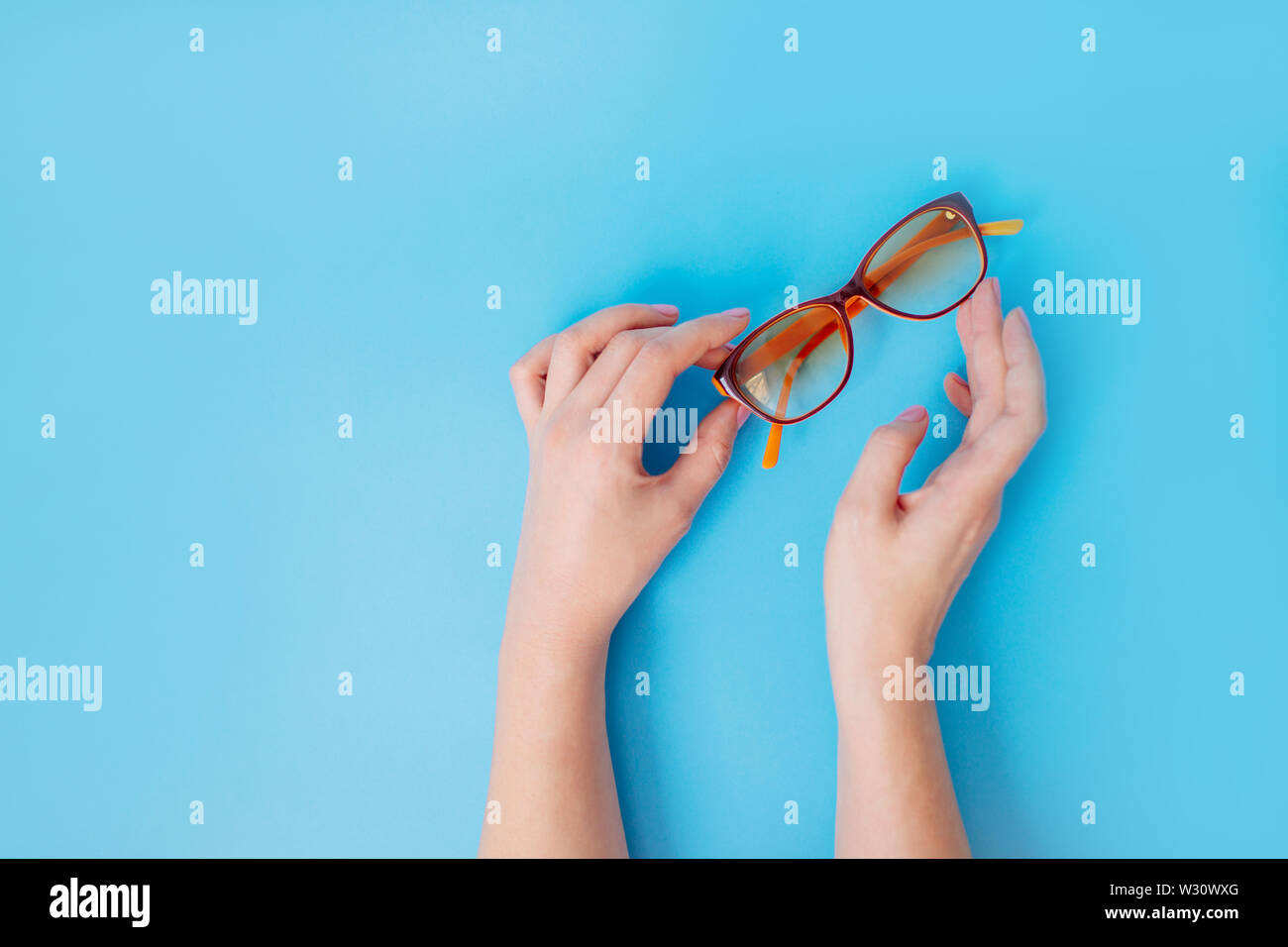 Female hands gently holding glasses with tips of the fingers on blue ...