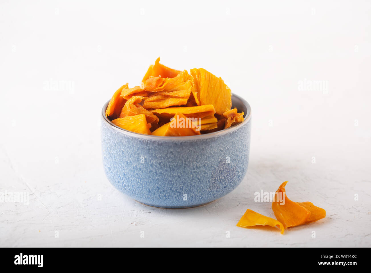 Mango chips close up in a blue bowl on a white background Stock Photo ...