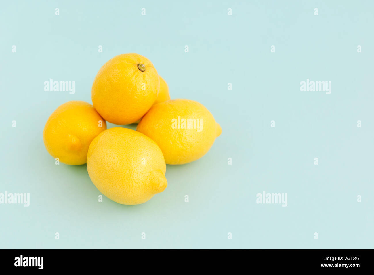 Pile of ripe yellow lemons on pale blue backgrounds. Copy space Stock ...