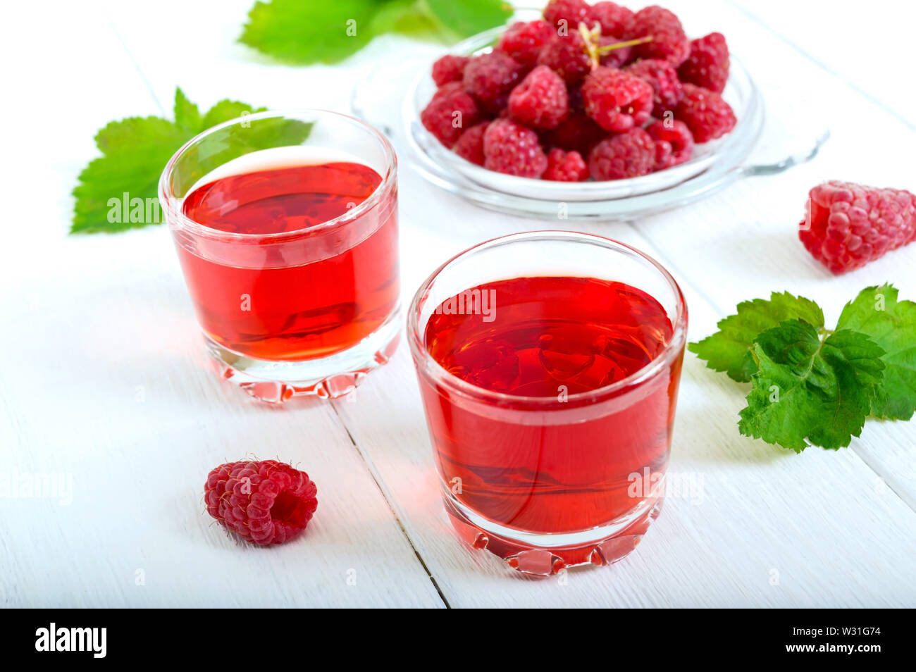 Raspberry liqueur in glass and fresh berries on a white background ...