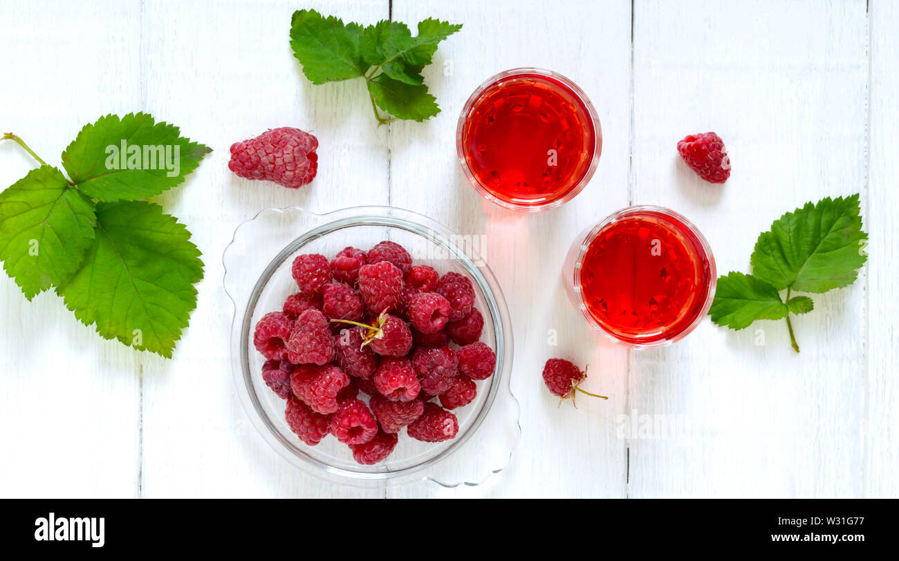 Raspberry liqueur in glass and fresh berries on a white background ...