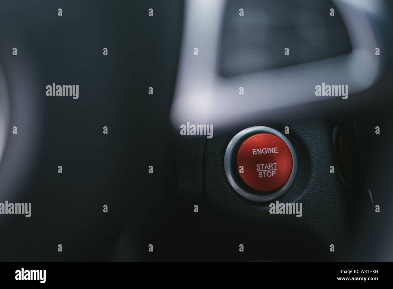 focus on red start stop button in car with unfocused steering wheel ...