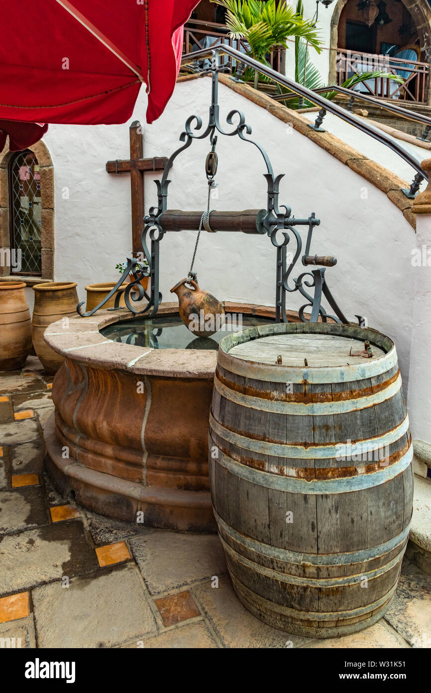 Old earthenware jug hanging on a rope above a rustic well and a vintage ...