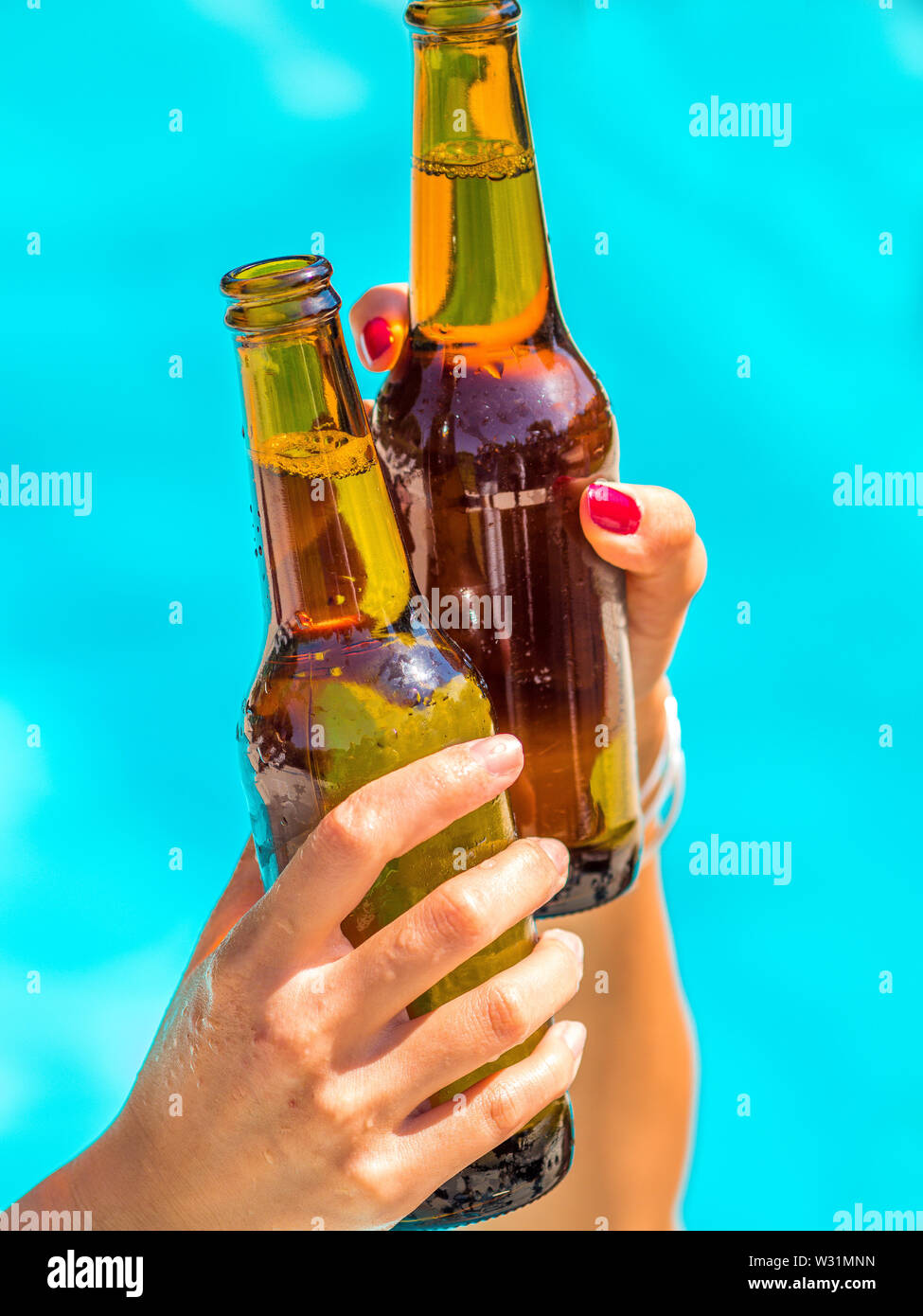 Female friends cheer clinking bottles of beer in their hands next to a ...