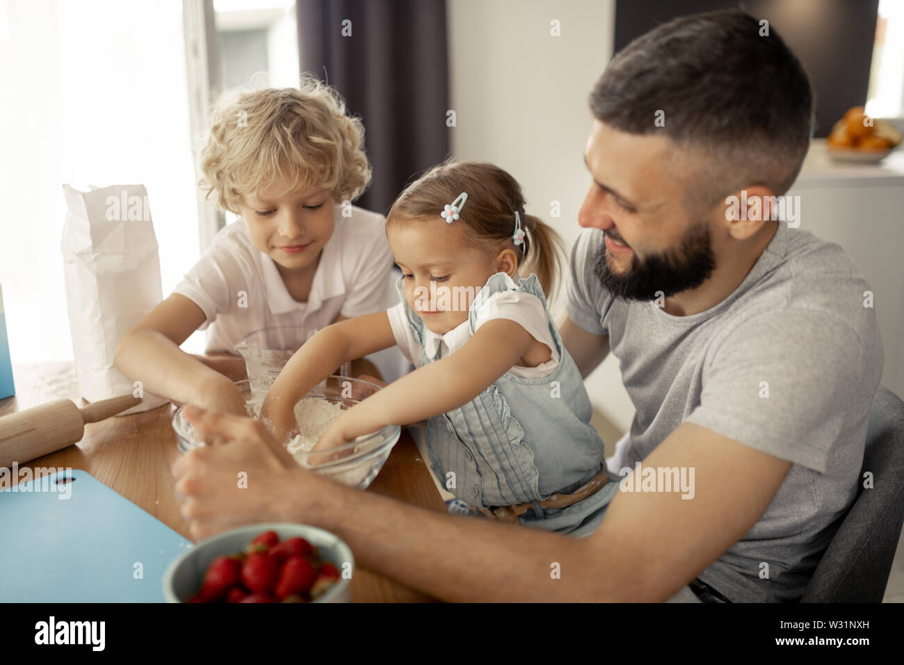 Fun activity. Joyful positive kids putting their hands in flour while ...