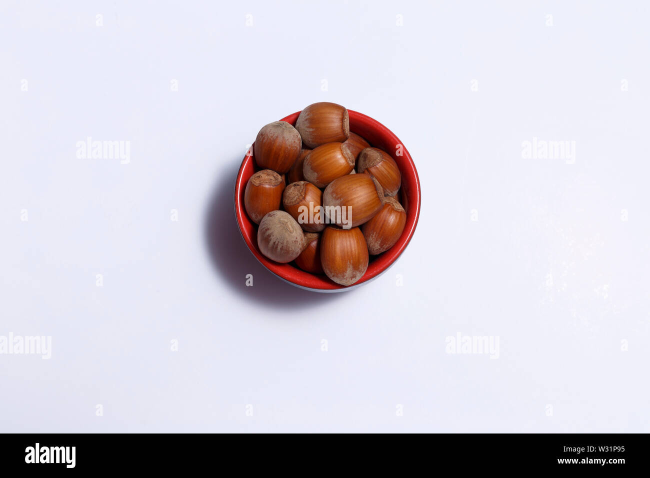 Top view of hazelnuts inside a red bowl isolated on white background ...