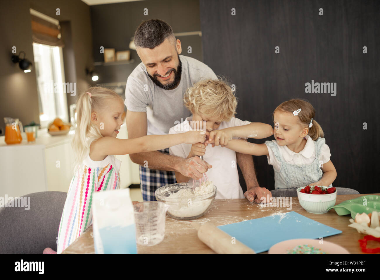 Common activity. Nice active children standing around the bowl with ...